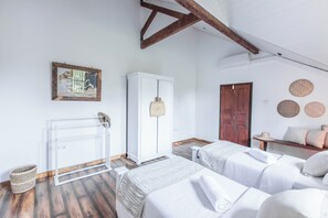 Quarto com duas camas, guarda-roupa, radiador e teto de madeira.