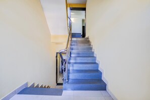 Uma escada com corrimão de metal e um hall revestido de carpete azul.