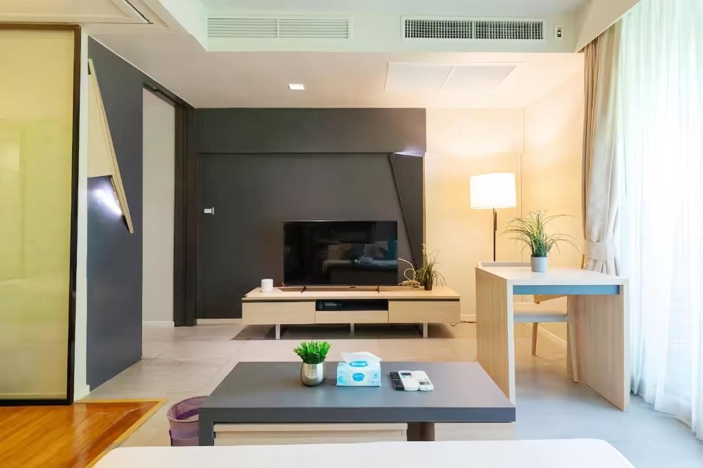 Uma sala de estar moderna com uma televisão de tela plana, uma mesinha com uma planta e um abajur.