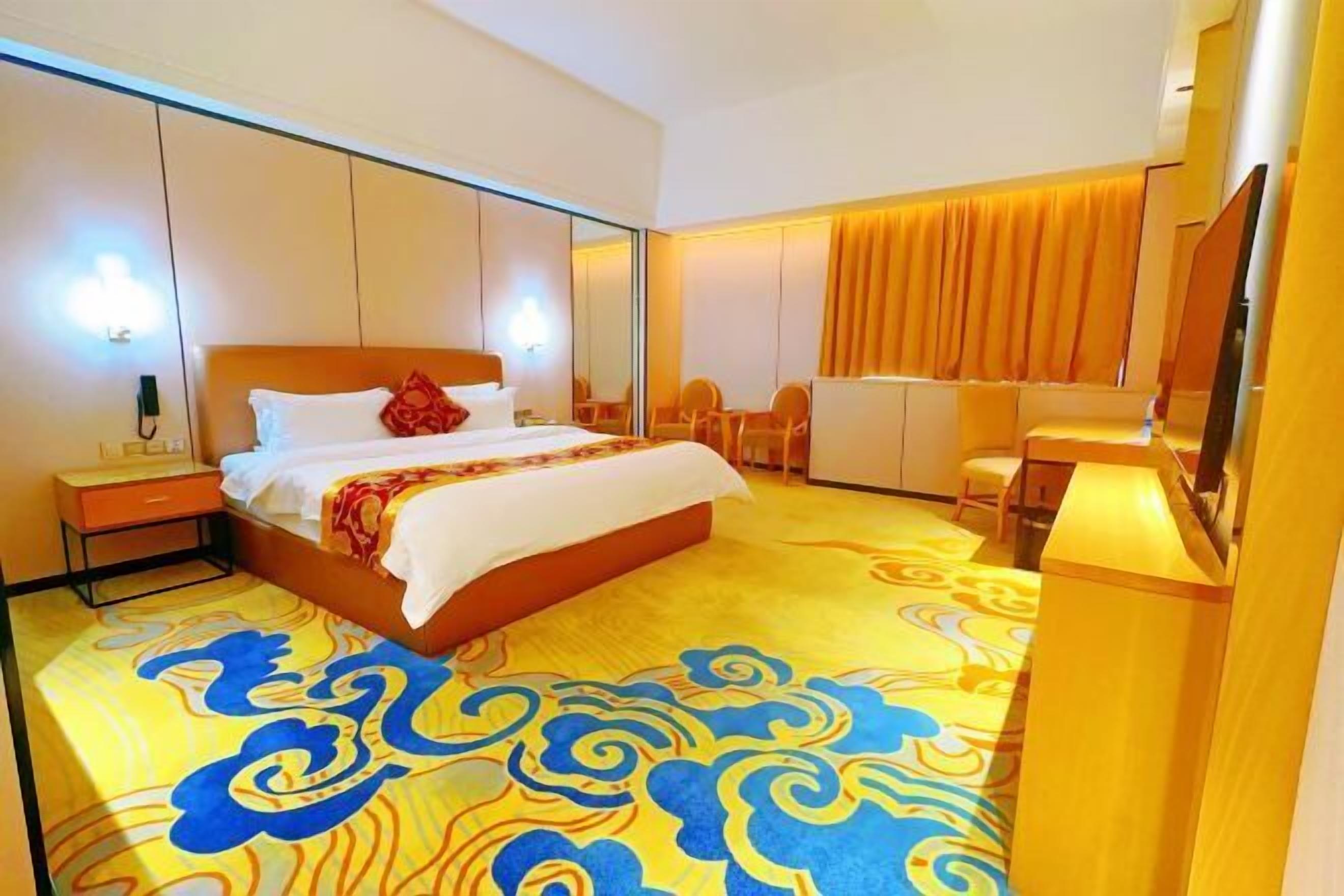 Quarto de hotel com cama, mesa de cabeceira e escrivaninha com cadeira.