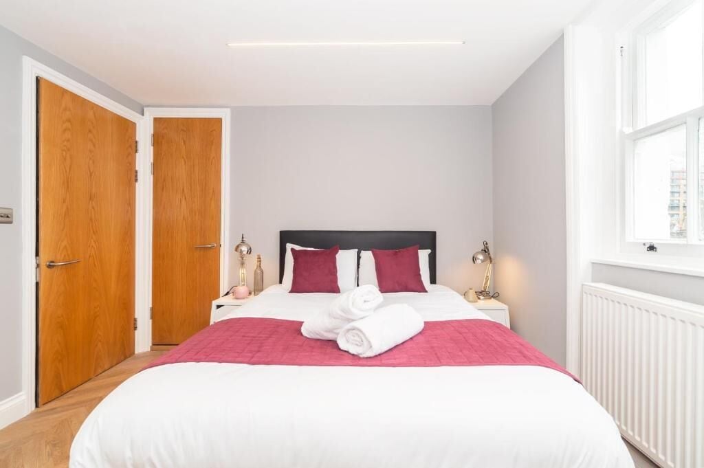 Quarto de hotel com uma cama, duas mesas de cabeceira, uma janela e uma porta.