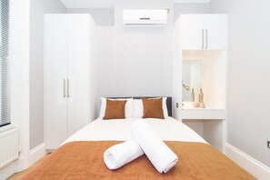 Quarto de hotel com uma cama, um guarda-roupa e um espelho.