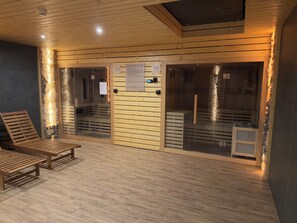 Uma sala de sauna com piso de madeira, bancos e portas de vidro.