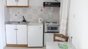 Uma cozinha compacta com mesa, cadeiras e eletrodomésticos básicos.