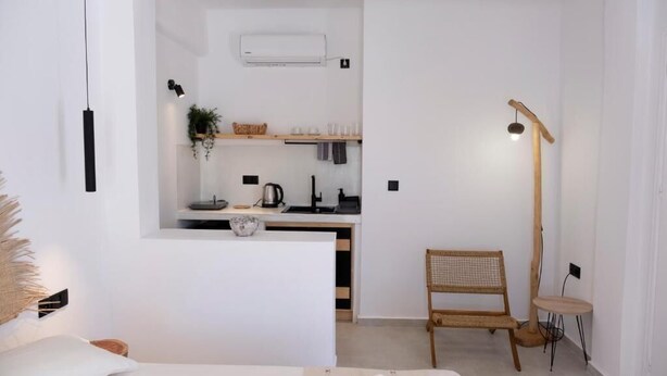 Um espaço compacto com cozinha compacta, cama, cadeira e abajur.