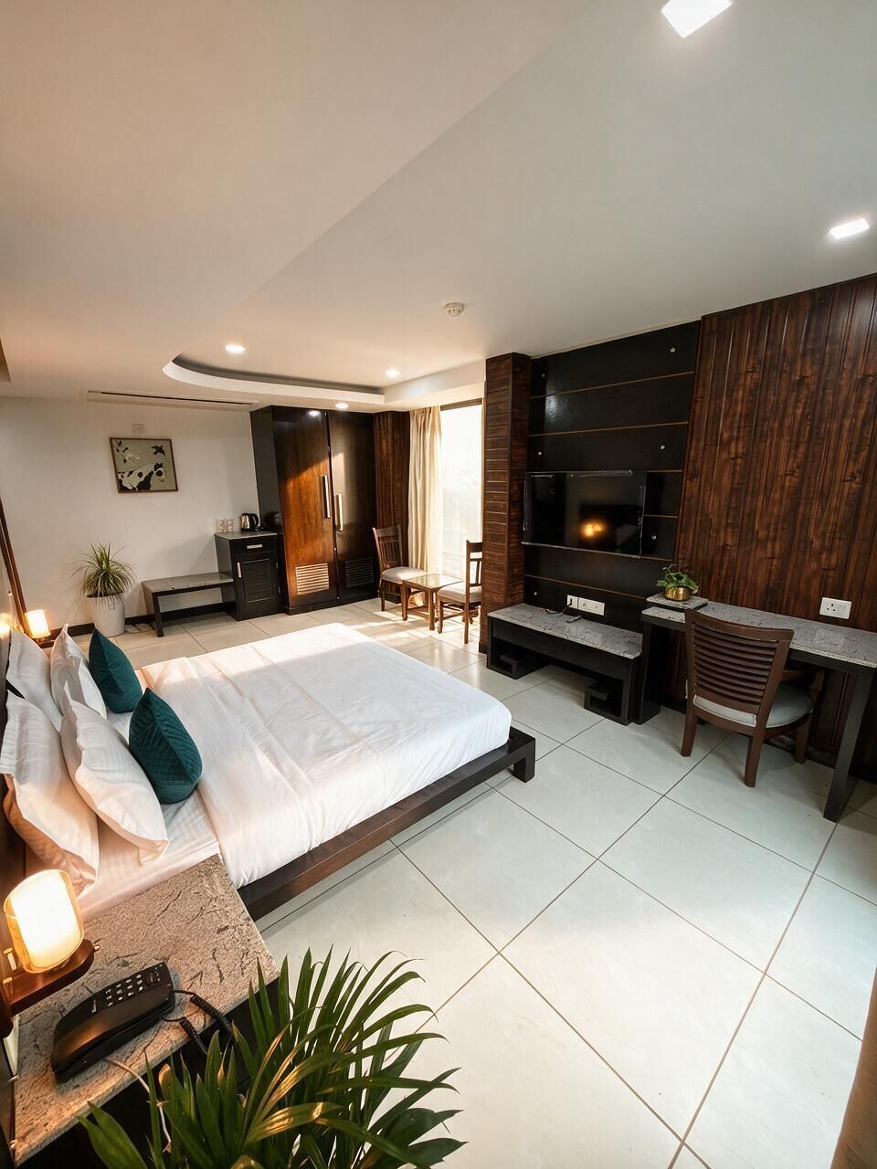 Quarto de hotel moderno com uma cama grande, uma escrivaninha, uma televisão e um espaço de estar.
