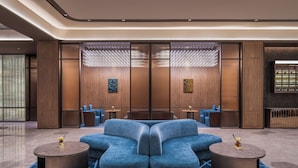 Um hall moderno com área de estar central, painéis de madeira e uma luminária decorativa.