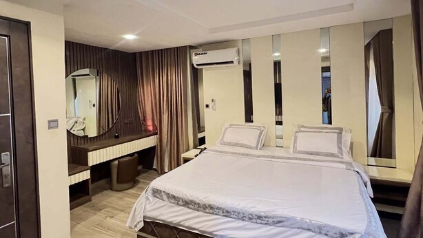 Quarto de hotel moderno com uma cama grande, uma toucador com espelho e um aparelho de ar condicionado.