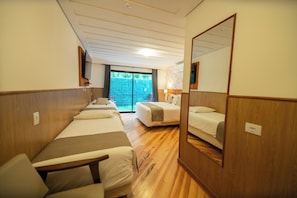 Quarto de hotel com duas camas de solteiro, um espelho grande e vista para o exterior.