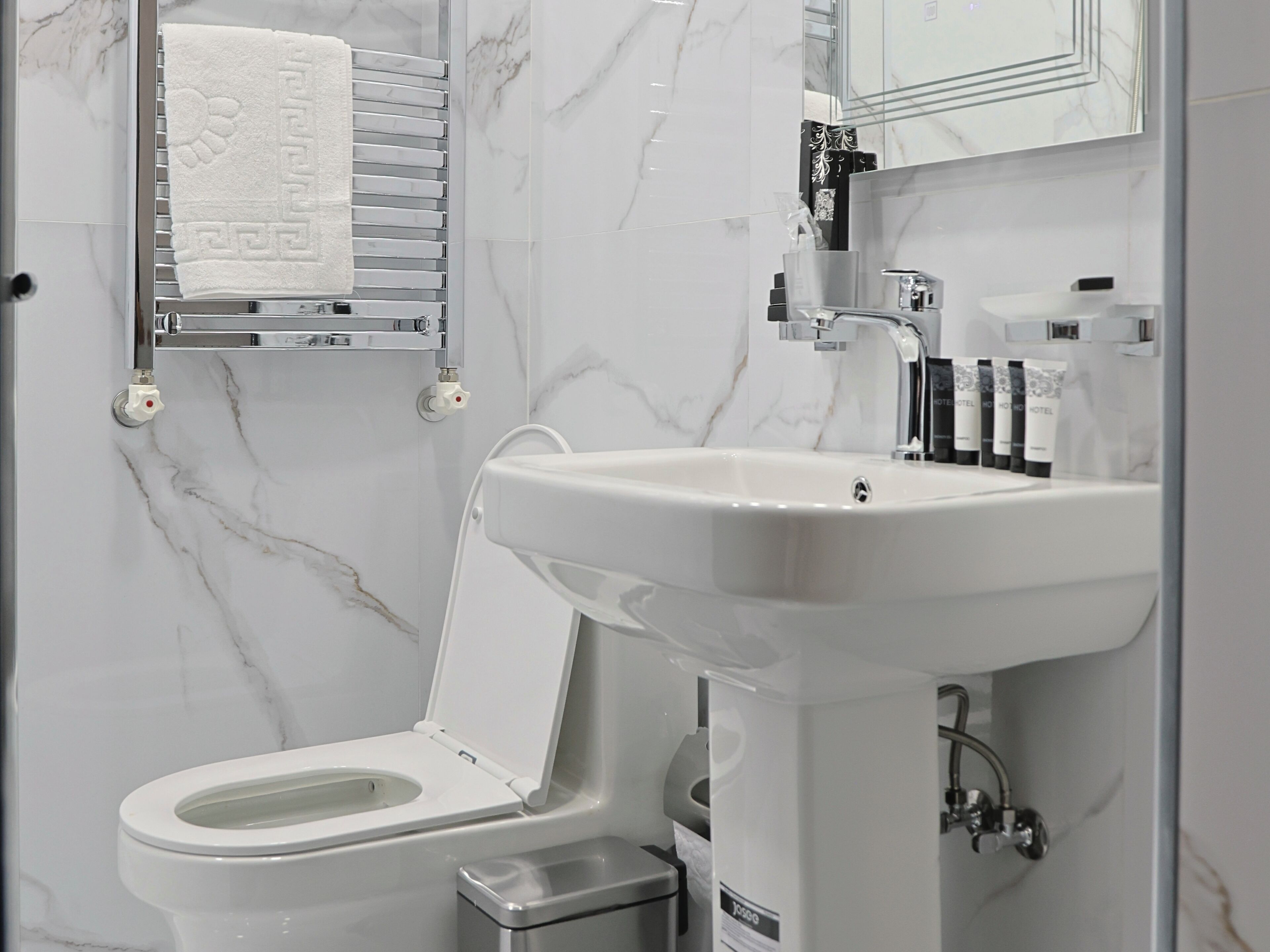 Casa de banho moderna com sanita branca, lavatório e porta-toalhas.