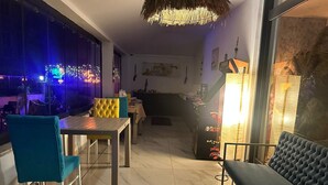 Uma sala de jantar com mesa e cadeiras, um sofá e um abajur decorativo.