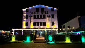 Um edifício com uma placa indicando 'CAYIR OTEL' na entrada, apresentando um caminho de acesso pavimentado e uma bicicleta estacionada em frente.
