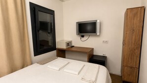 A hotel room with a bed, a TV, a desk, and a wardrobe.