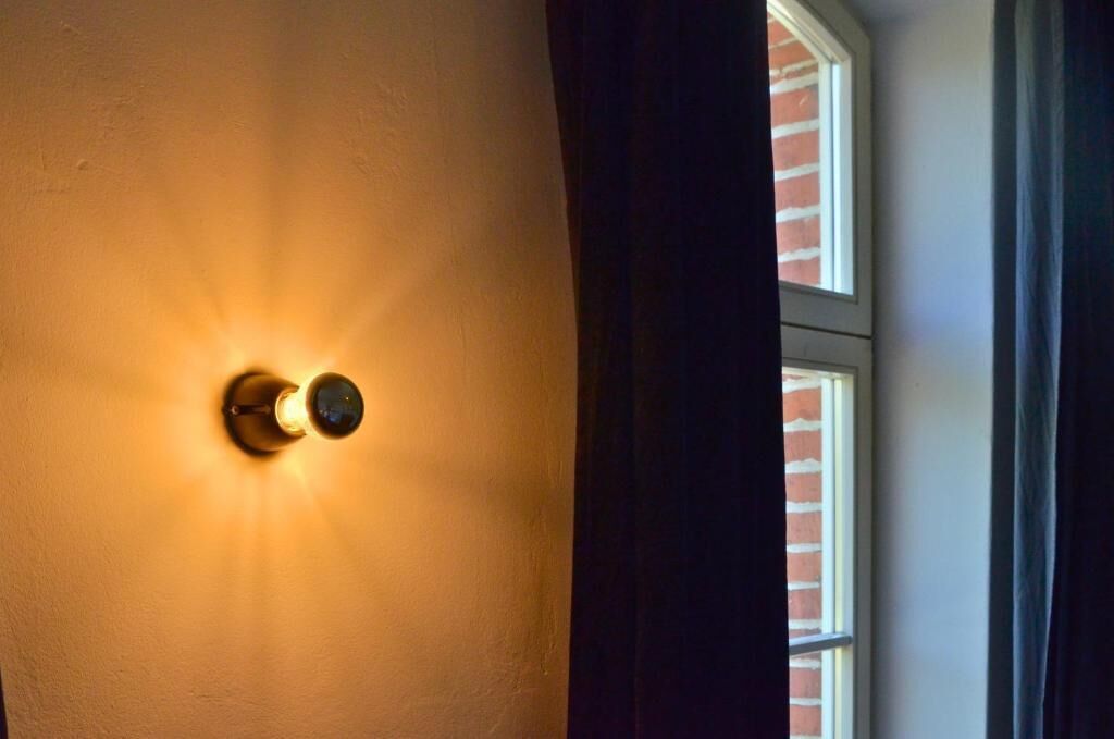 Uma porta com um luminário e uma janela com cortinas.