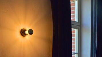 Uma porta com um luminário e uma janela com cortinas.