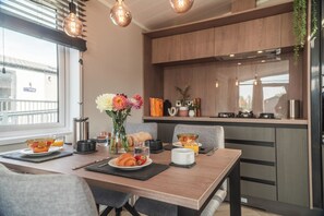 Cozinha moderna com armários de madeira, mesa de jantar com itens de café da manhã e vista para a cidade.