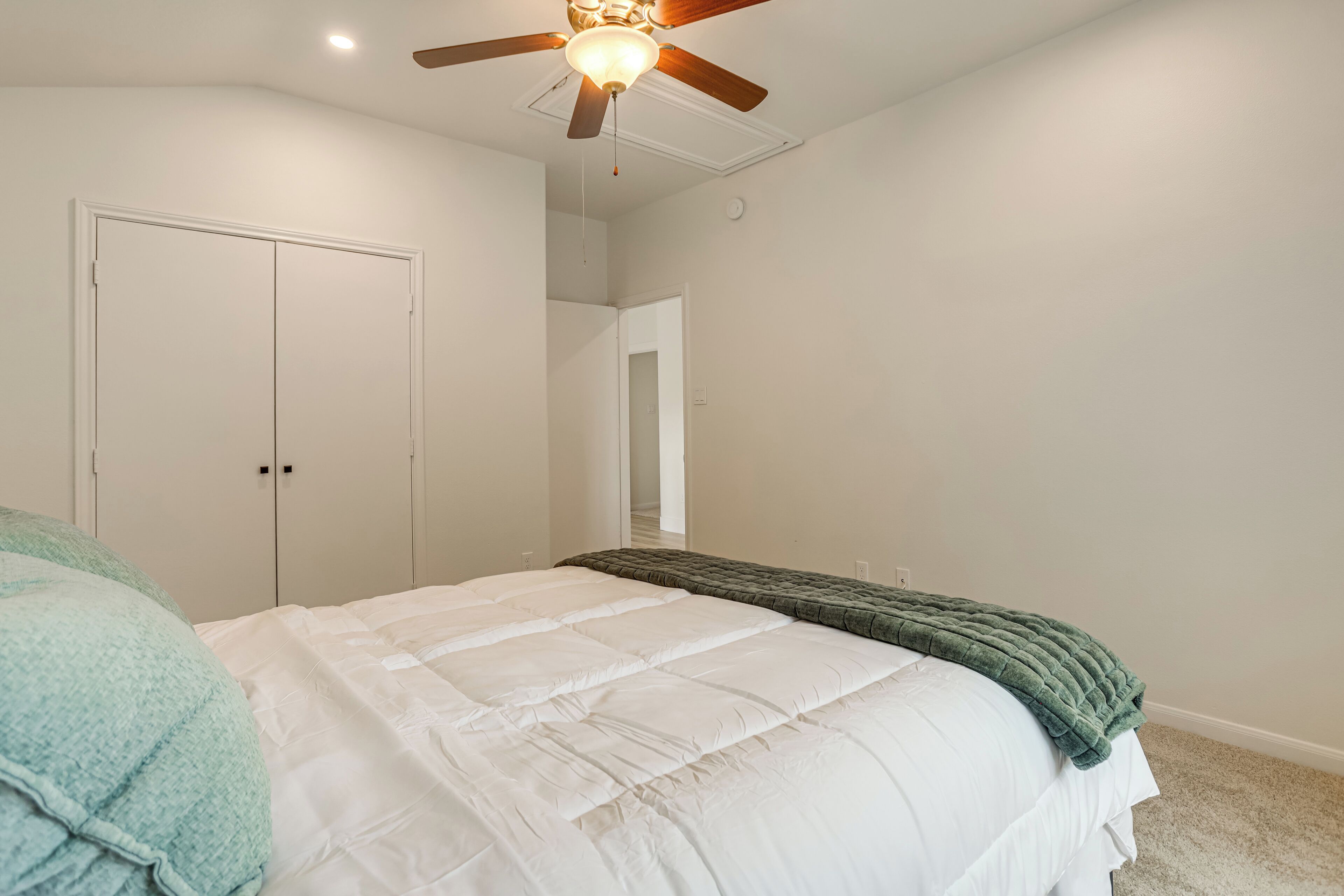 Quarto com cama, ventilador de teto e porta.