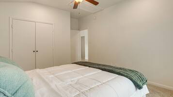 Quarto com cama, ventilador de teto e porta.