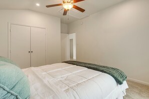 Quarto com cama, ventilador de teto e porta.