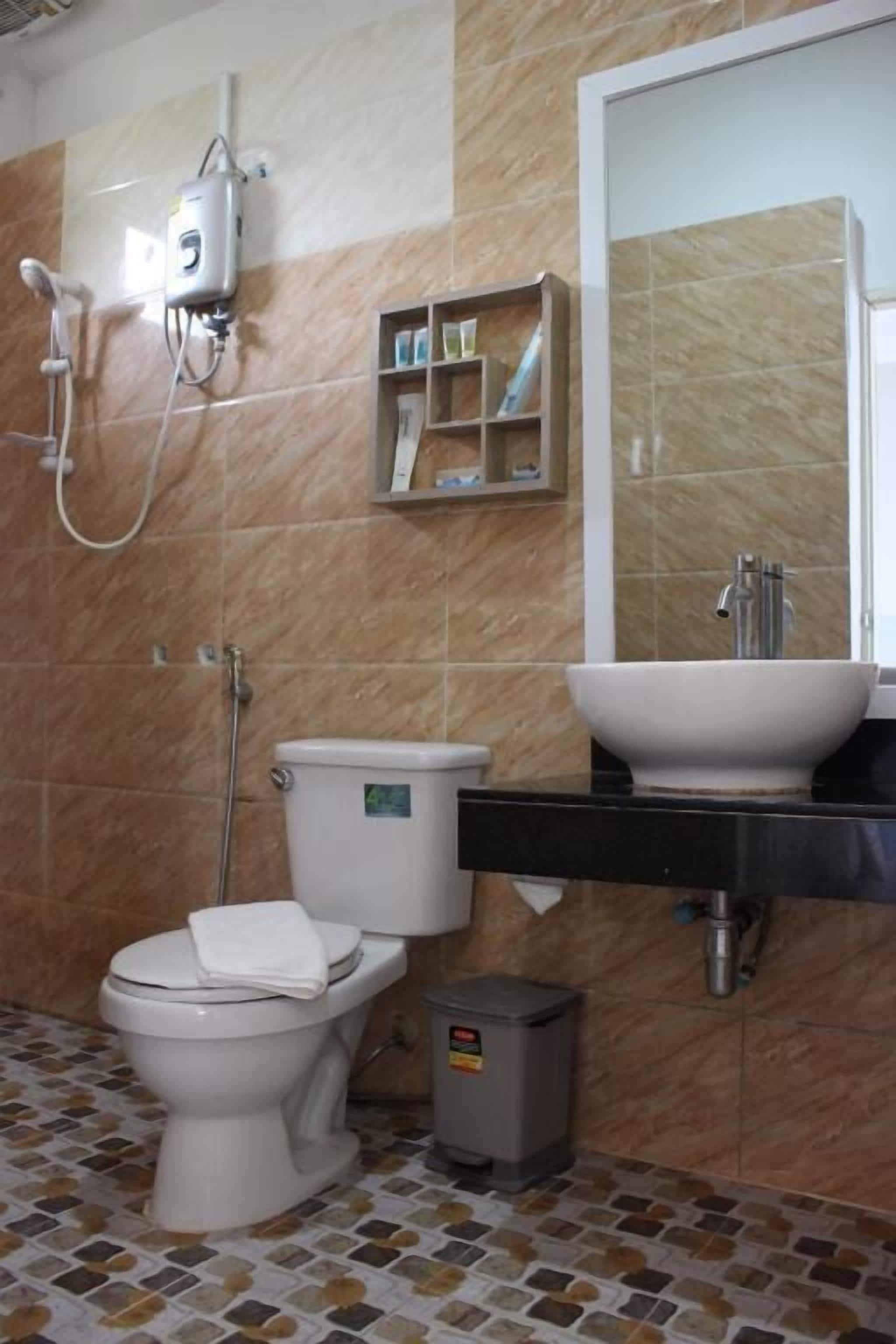 A bathroom with a toilet, sink, mirror, shower, and tiled floor.