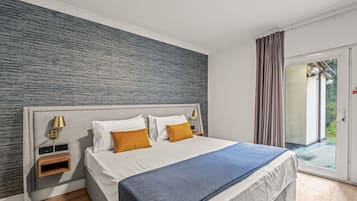 Quarto de hotel com cama, mesa de cabeceira, abajur e vista para o exterior.