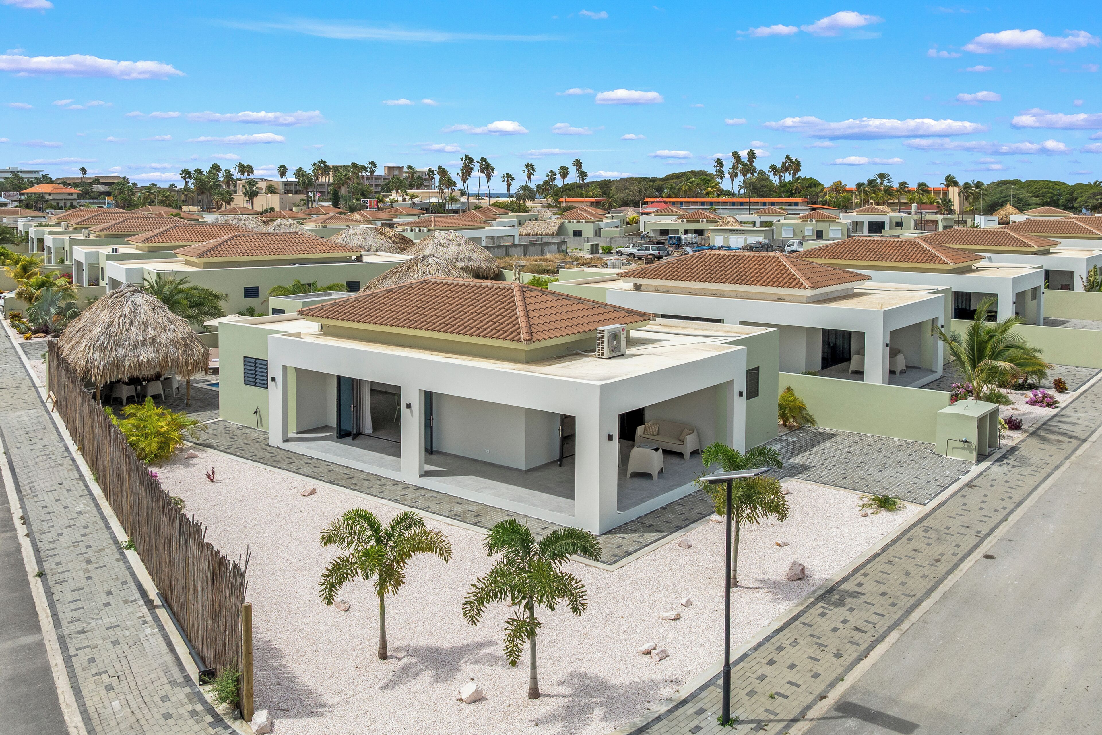 Um resort com villas modernas, cada uma com telhado de azulejos e área externa coberta.