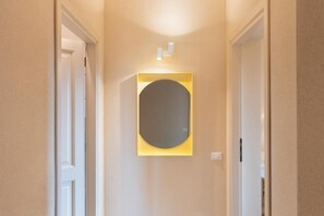 Corredor com uma porta à esquerda e um ponto de luz fixado na parede, acima de um nicho.