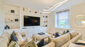 Uma sala de estar moderna com televisão de tela plana, armários brancos e uma janela grande.