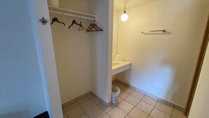 Casa de banho com sanita, lavatório e suporte de toalhas com ganchos.