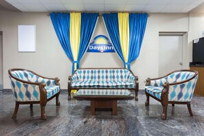 Uma área de recepção com um sofá e duas poltronas, uma placa da Days Inn e um quadro branco na parede.