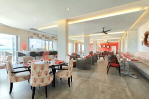 Uma ampla sala de jantar com pé direito alto, iluminação moderna e disposições de assentos confortáveis.