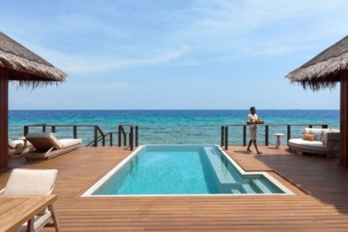 Área da piscina com espreguiçadeiras, piscina e vista para o oceano.