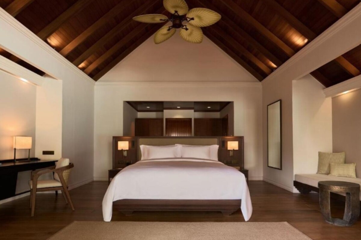 Quarto com uma cama grande, uma escrivaninha e uma cadeira.