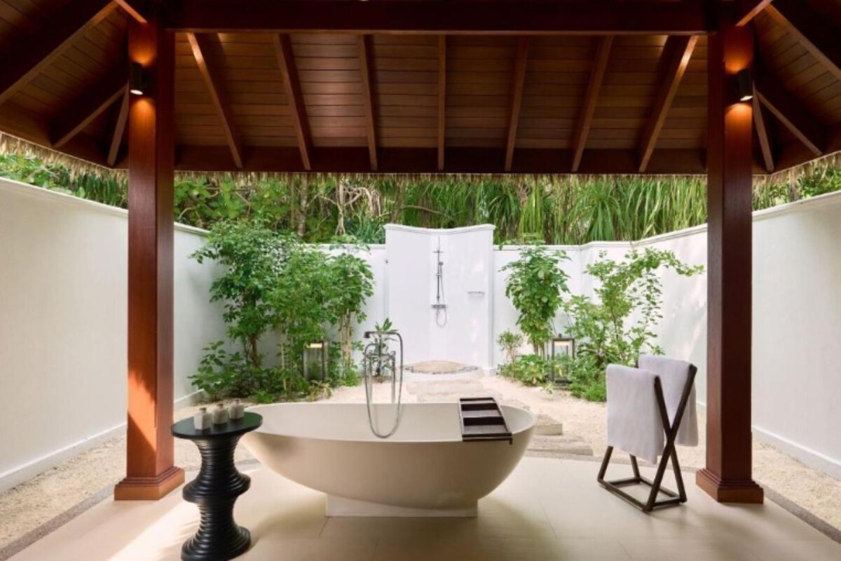 Casa de banho privada ao ar livre com banheira independente, uma pequena mesa e um porta-toalhas.