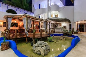 Um hall de hotel com piscina, deck de madeira e área de bar.