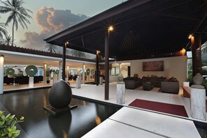 Um lobby moderno com piscina, áreas de estar e um mural tropical.