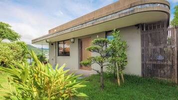 Uma casa moderna com telhado curvo, pequeno alpendre e quintal cercado.