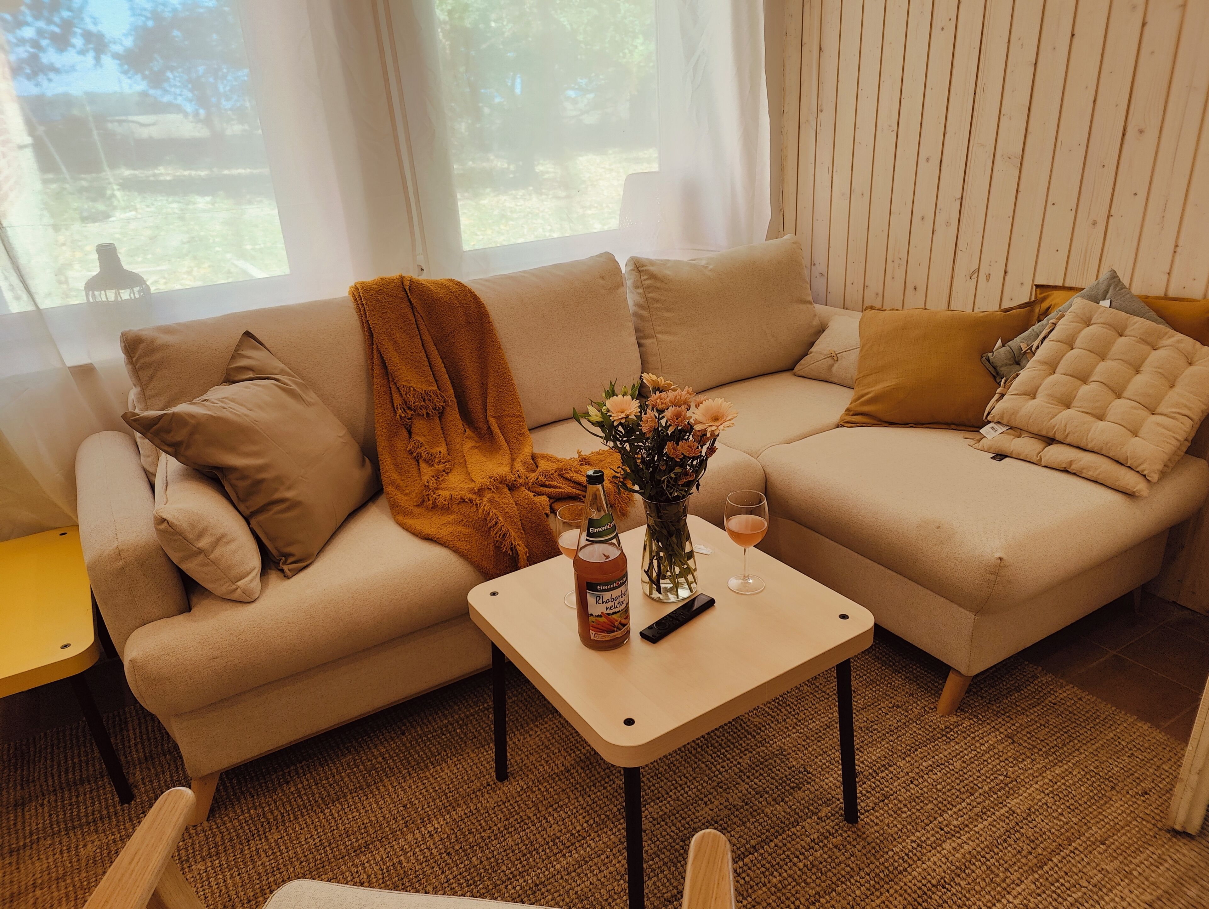 Uma sala de estar aconchegante, com um sofá, uma mesa de centro e um vaso com flores.