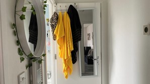 Uma casa de banho com espelho, um porta-toalhas com vários toalhas e uma porta que dá para outro quarto.