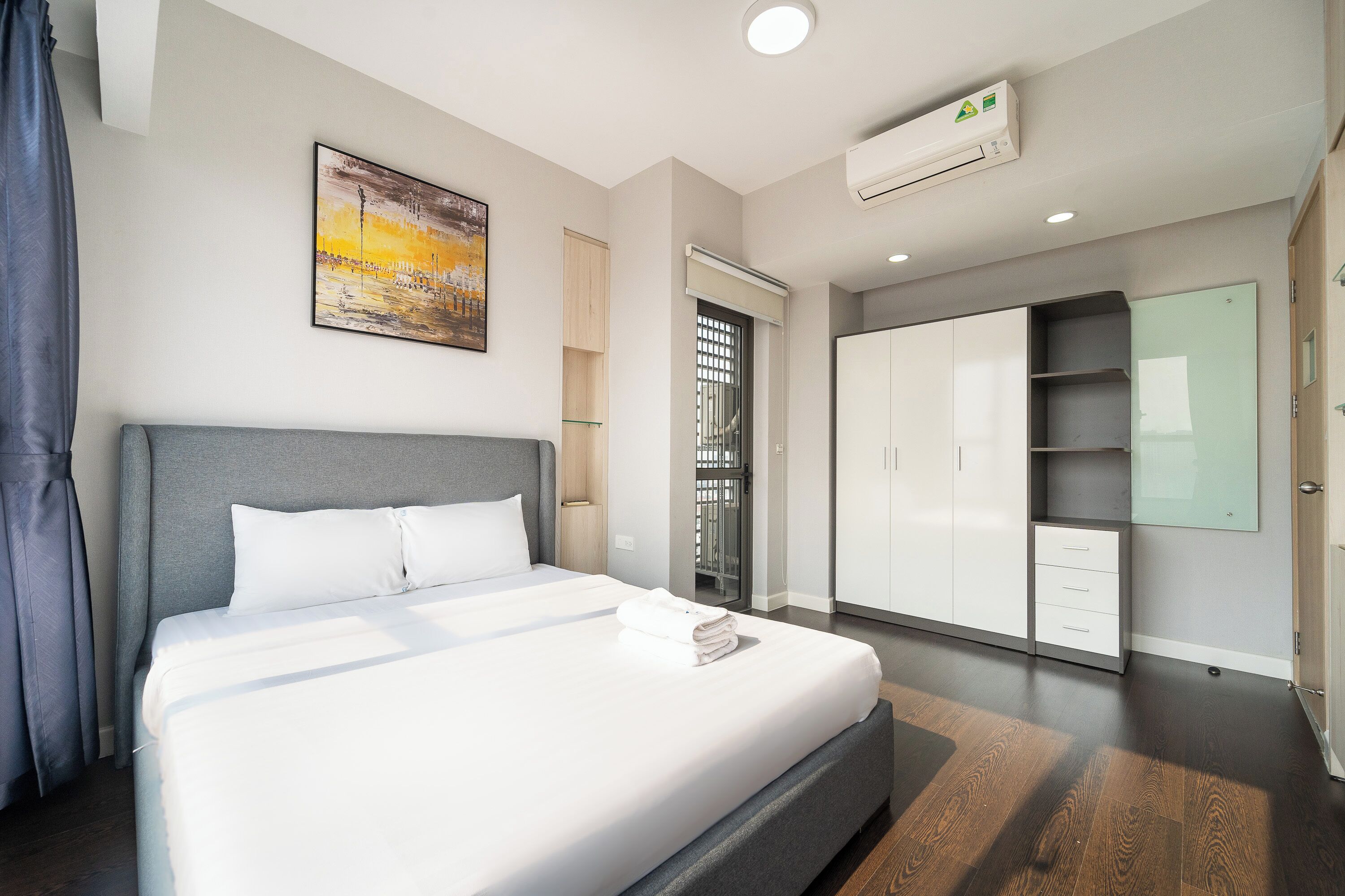 Quarto de hotel moderno com uma cama grande, um quadro, um ar condicionado e um guarda-roupa.