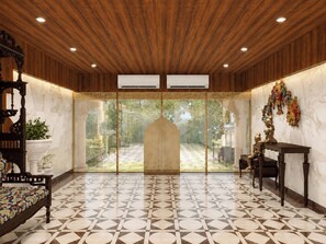 Quarto com piso estampado, teto de madeira e vista através de porta de vidro para área externa.