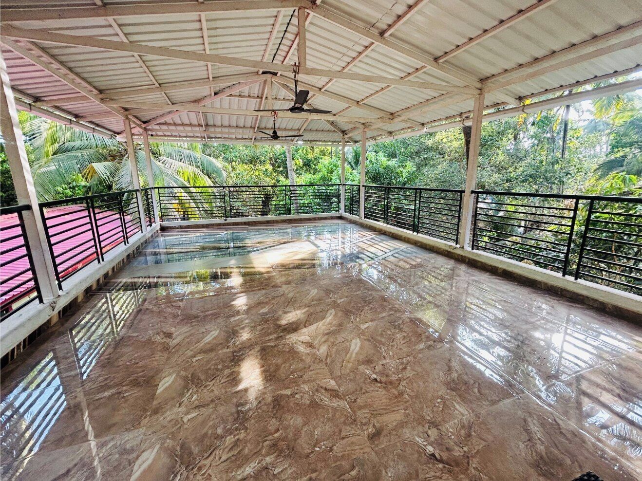 Um espaço interno com piso de azulejos, corrimãos de metal e um ventilador de teto.