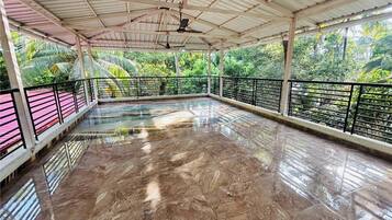 Um espaço interno com piso de azulejos, corrimãos de metal e um ventilador de teto.