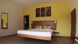 Quarto com uma cama grande, cabeceira de madeira, mesa de cabeceira e uma porta.