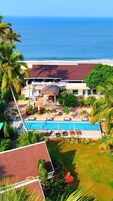 Um resort com piscina, espreguiçadeiras e vista para o oceano.