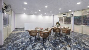 Uma sala de conferências com piso de mármore, cadeiras de vime, um quadro branco e uma vista através de grandes janelas.