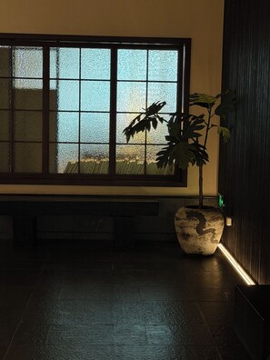 Um quarto com uma janela ampla, um banco e um vaso de planta.