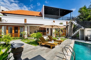 Uma casa moderna de dois andares com piscina, área de estar externa e escadaria que dá para uma varanda.