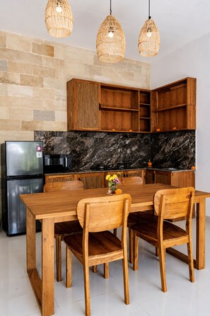 Uma cozinha moderna com armários de madeira, bancada de mármore e uma mesa de jantar com cadeiras.