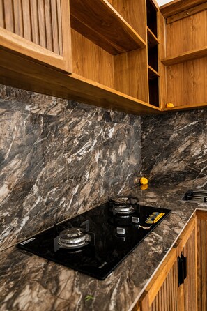 Uma cozinha com fogão preto, armários de madeira e painel de fundo de mármore.